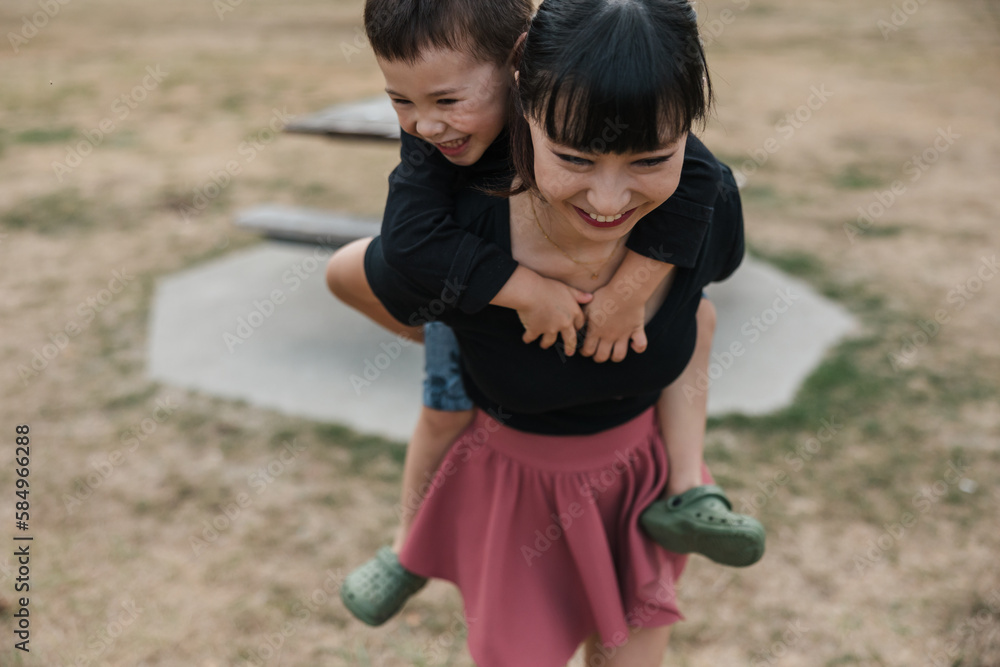 Mom giving shoulder ride to toddler son outside. Stock Photo | Adobe Stock
