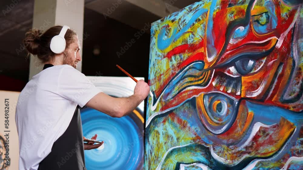 Stockvideon A talented innovative artist in white headphones paints ...