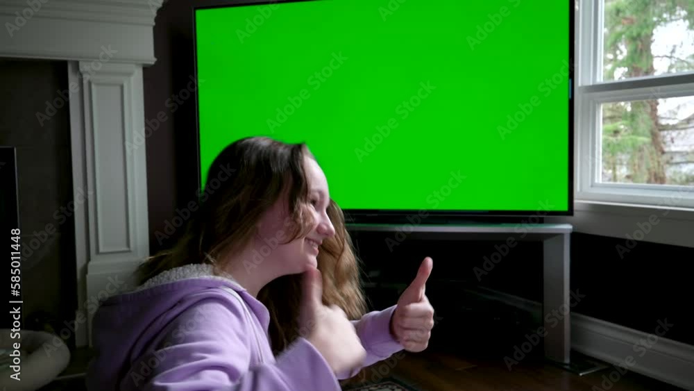 teenage girl sits admiringly in front of a big green chroma key tv ...