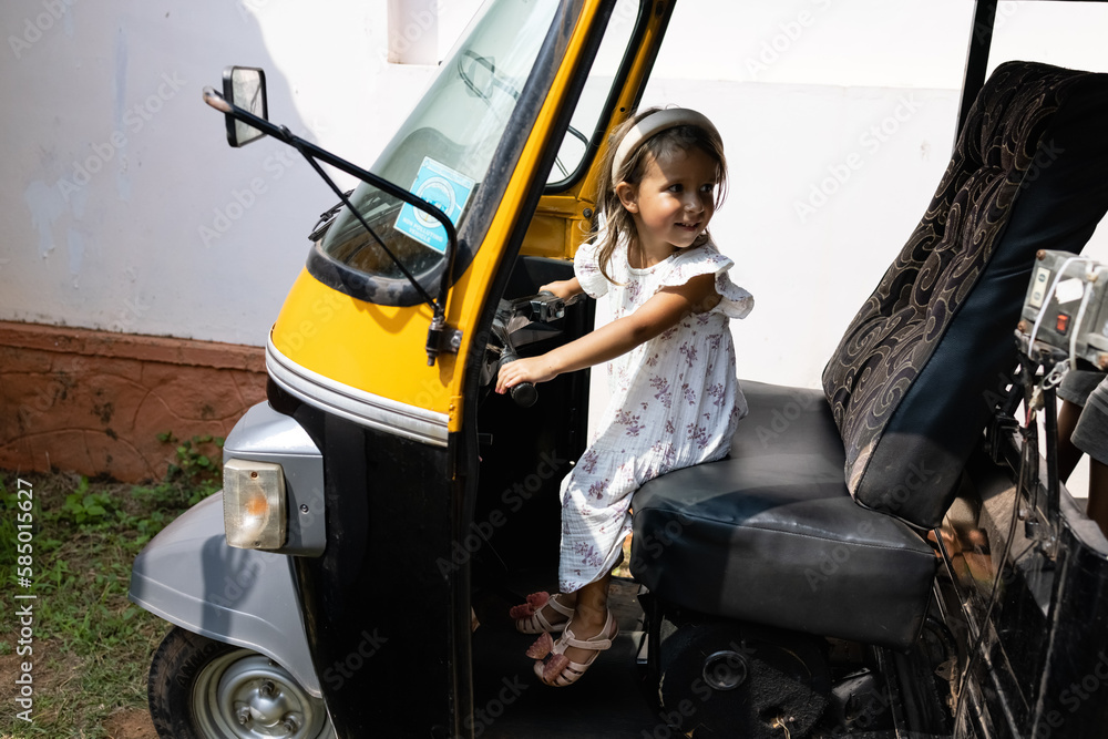 Caucasian girl with dark hair in a white dress poses behind the wheel ...
