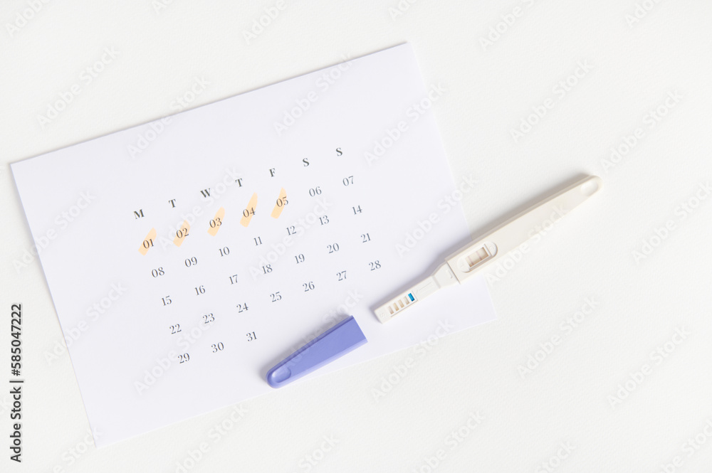 Flat lay. Positive pregnancy inkjet test and a calendar with the days ...