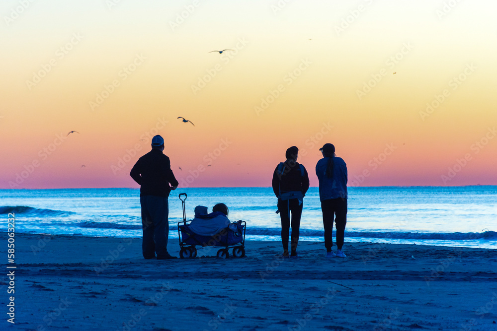 North Myrtle Beach, SC: Young family watching the colorful sky lighten over the Atlantic Ocean ...