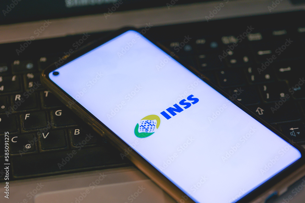 Foto de A logo do INSS na tela de um telefone celular que está sobre um ...