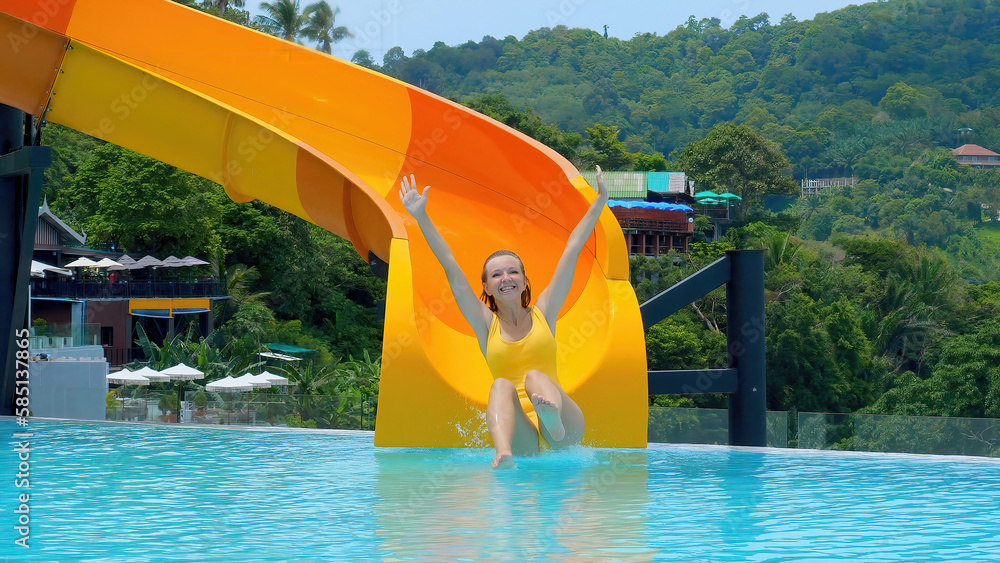 Woman in blue swimwear slides down a water slide at an aquapark resort ...