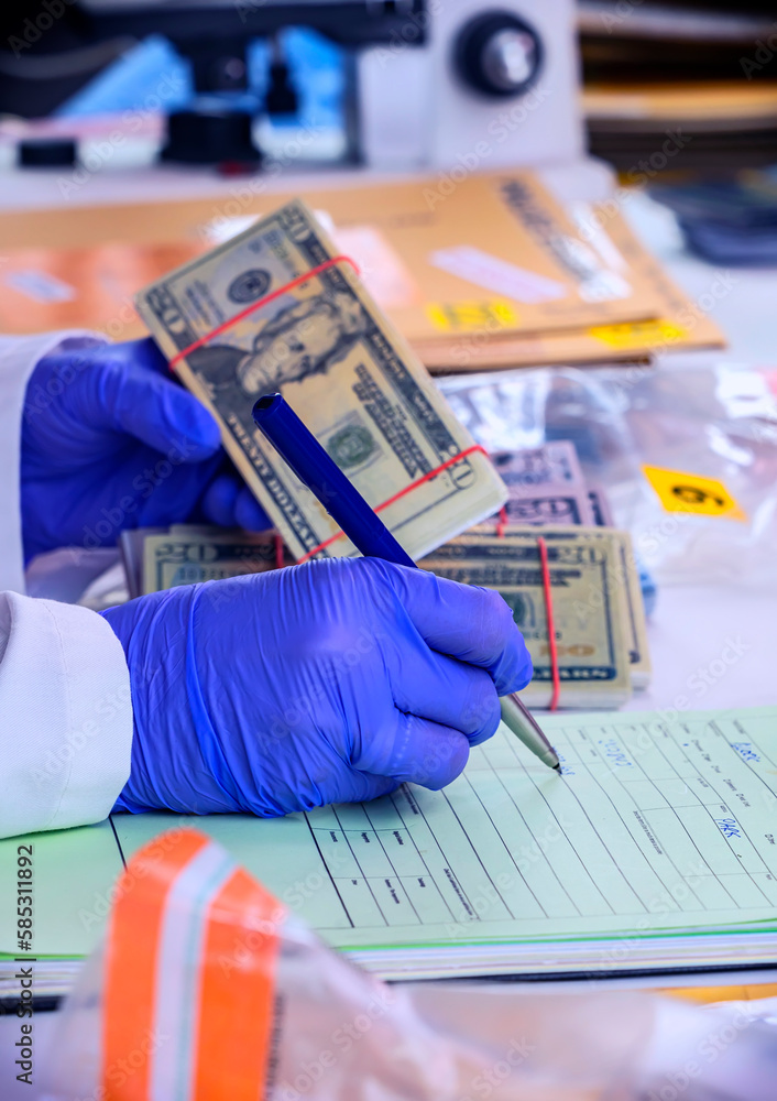 Police scientist notes down serial numbers of U.S. bills from a crime ...