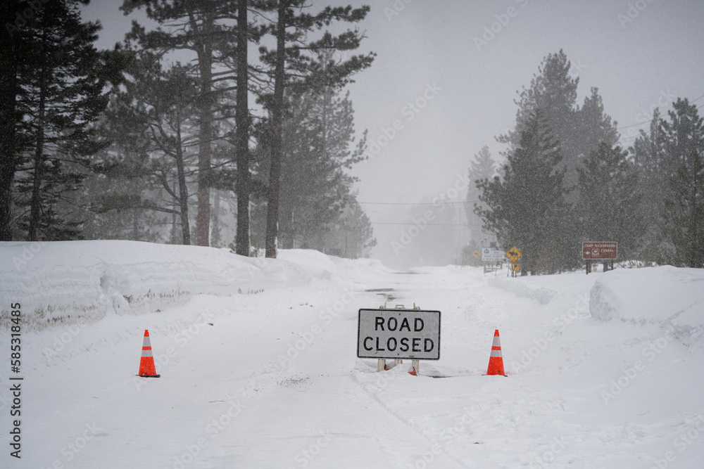 Road closed sign during winter storm with sign and red cones blocking ...