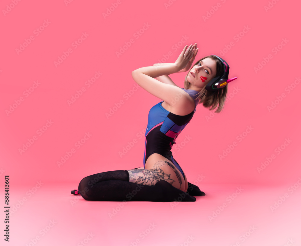 Sexy Gamer Girl In A Revealing Bright Bodysuit And Gaming Headset On A Pink Background ภาพถ่าย