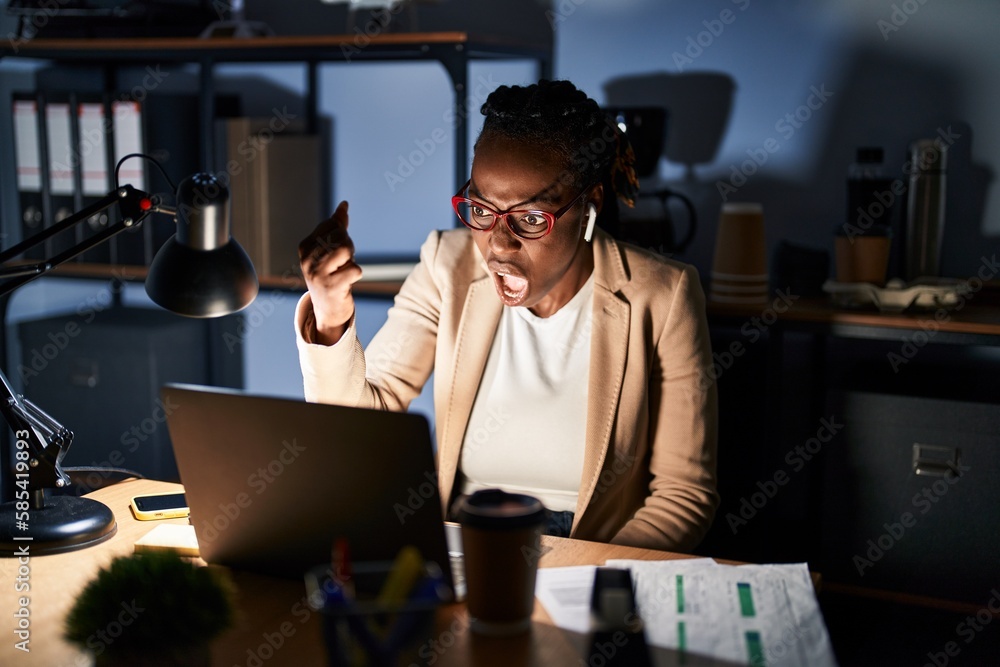 Beautiful black woman working at the office at night angry and mad ...
