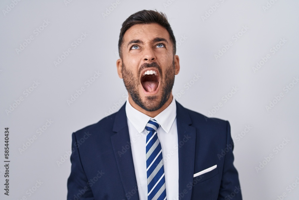 Handsome hispanic man wearing suit and tie angry and mad screaming ...