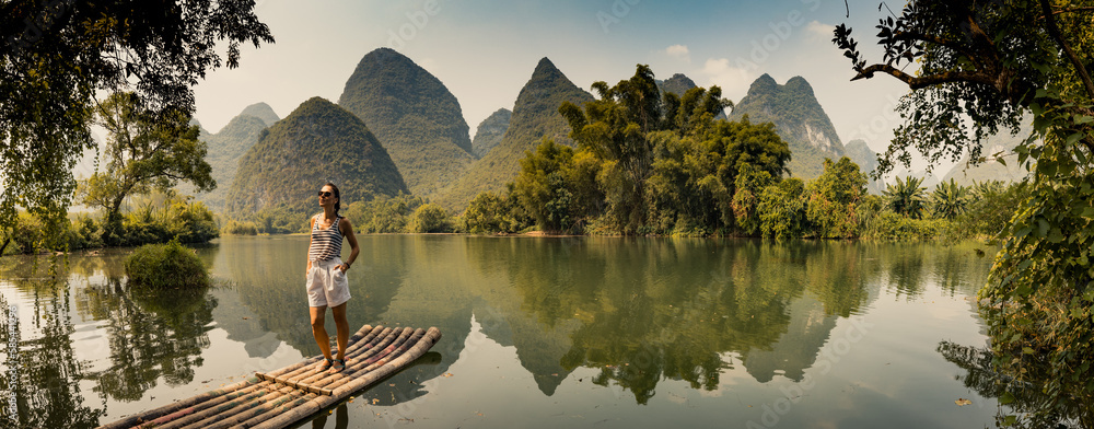 Girl standing on a raft on a Yalong River with beautiful scenery of ...