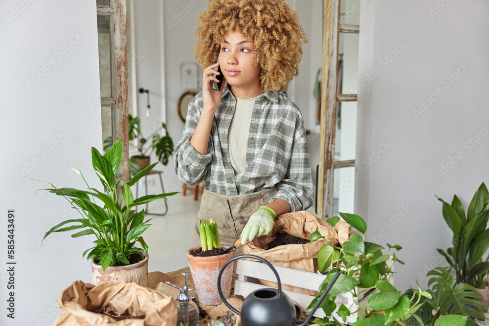 Busy female botanist works at home in garden transplants flowers in new ...