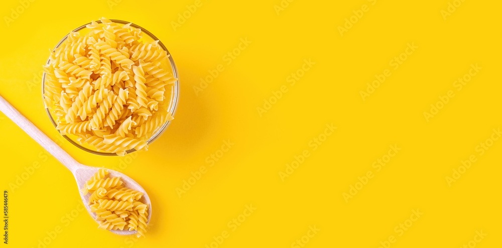 Fusilli spaghetti pattern, food background. Bowl and wooden spoon with ...