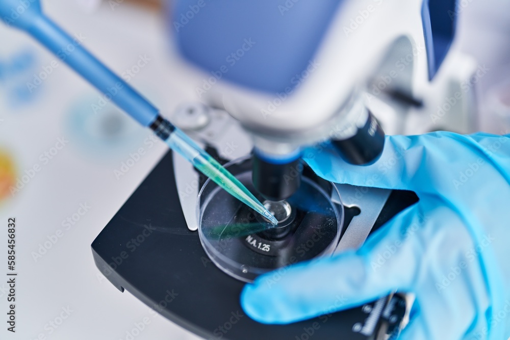 Young woman scientist pouring liquid on sample using microscope at ...