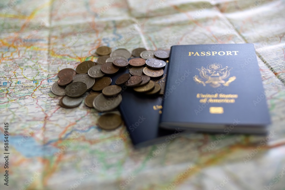 two passports and foreign coins on open road map for travel or ...