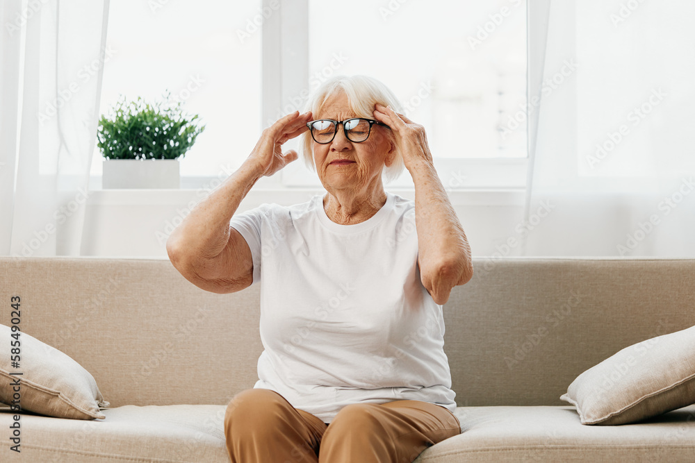 Elderly woman severe pain in the head sitting on the couch, health ...