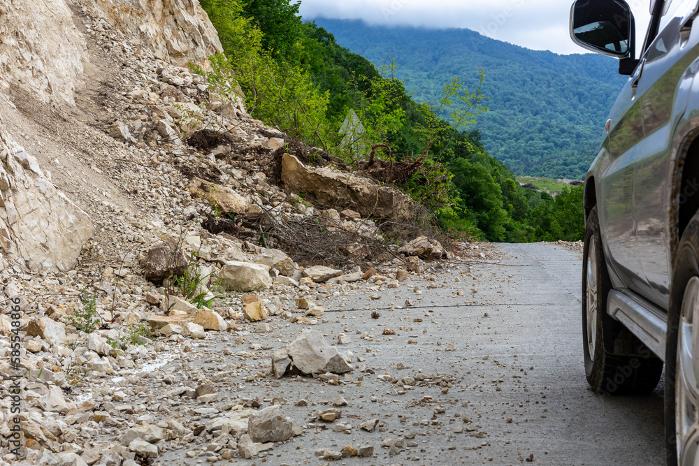 Limestone rockfall and landslide fallen on a tarmac road with car ...