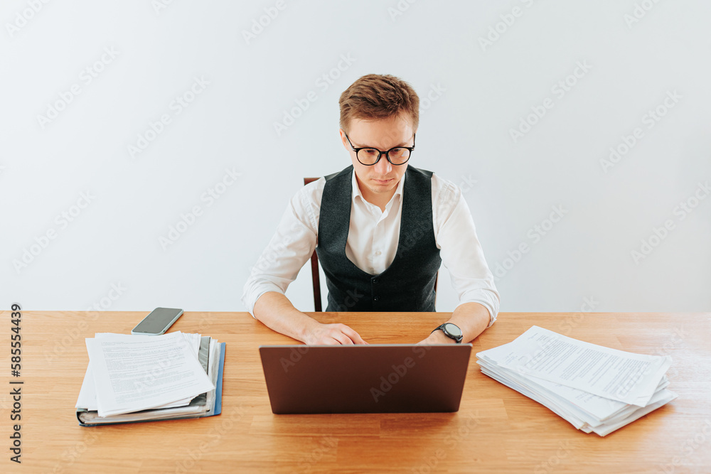 A male office worker in his home office, surrounded by paperwork and ...
