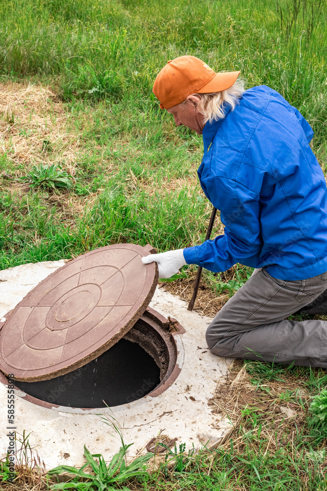 the man opened the cover of the sewer manhole to pump out the sewage ...