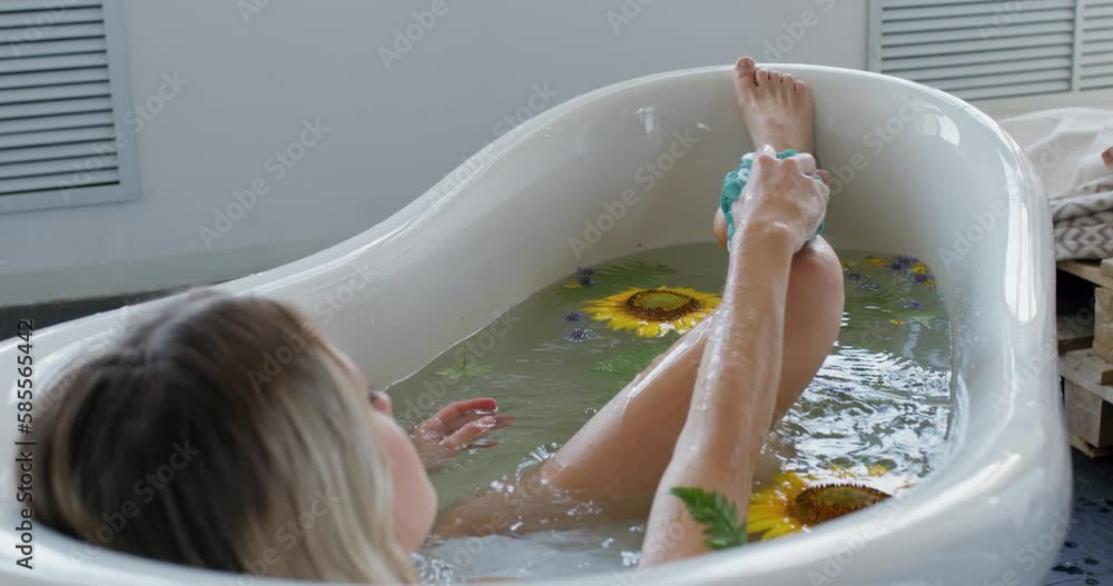 unrecognizable beautiful caucasian female taking bath washing legs ...