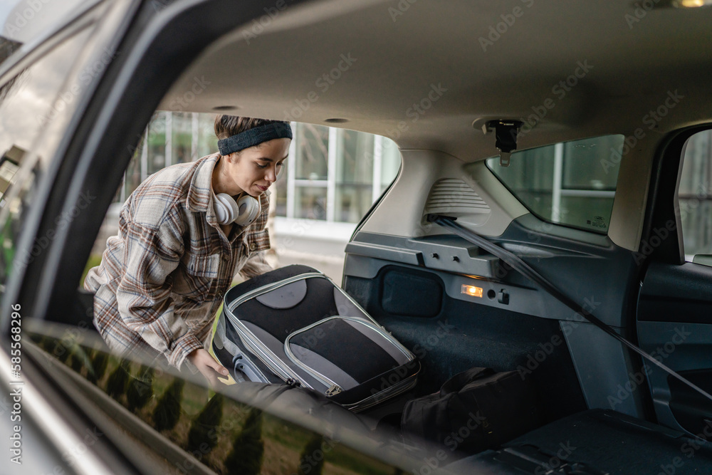 one young woman pack luggage baggage suitcase in the trunk of the car ...