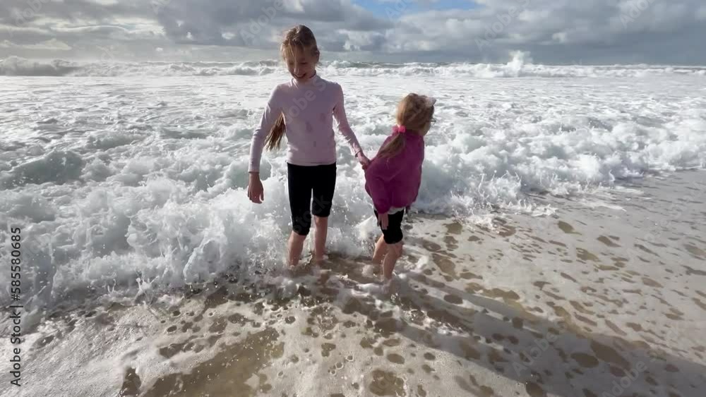 Children run along the coast of the Atlantic Ocean. Two little sisters ...