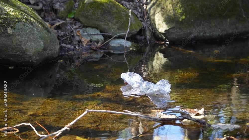Plastic bottle floating in a river, littering rubbish in nature ...