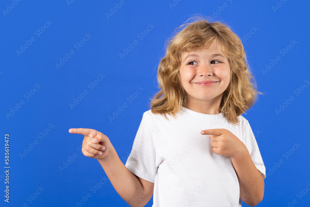 Child boy pointing away on blue isolated studio background. Portrait of ...