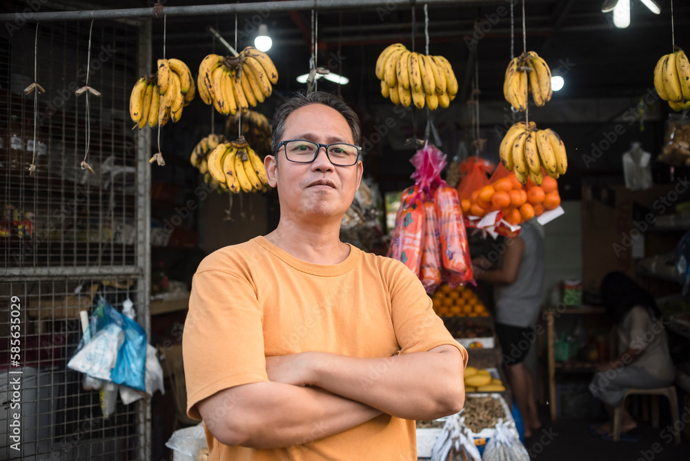 A middle aged Filipino fruit vendor, posing in front of his open-air ...