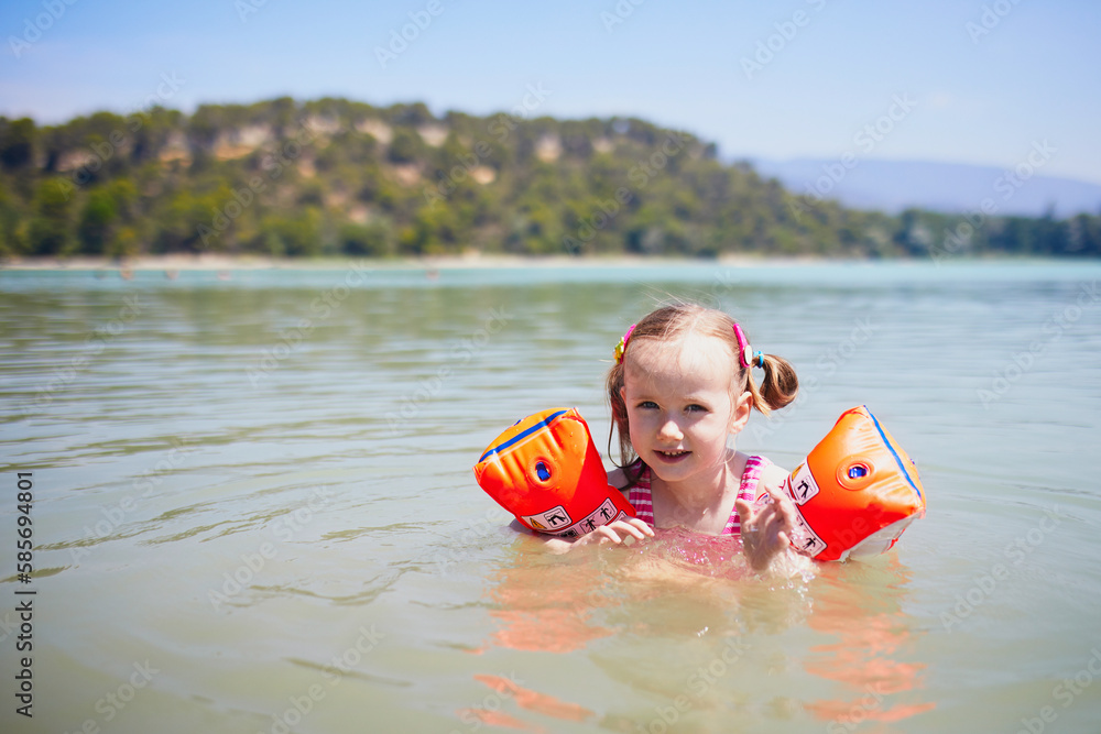 Foto de Happy little girl swimming with water wings in the lake called ...
