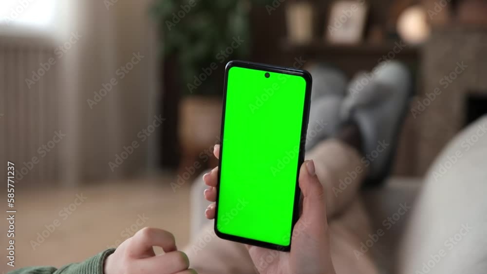 Point of View of woman lying on couch using smartphone with chroma key green screen, doing ...
