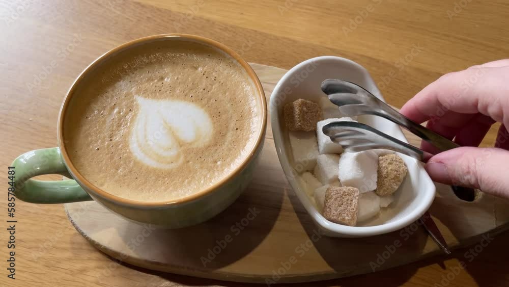 Top view of person hand puts a lump of sugar in the coffee. Breakfast ...