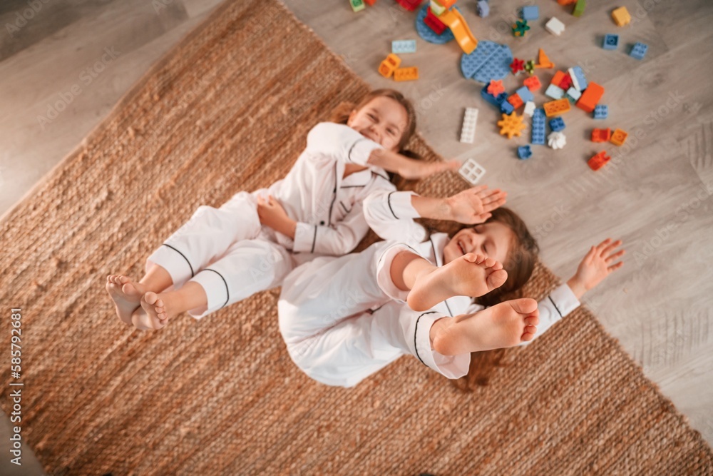 Top view. Lying down. Construction plastic toys. Two little girls are ...