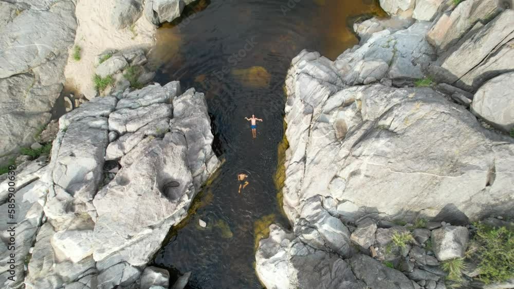 Personas nadando en un rio rodeado de piedras, plano de dron cenital ...