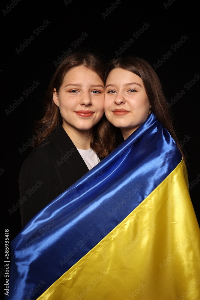 portrait of two young girls sisters on a black background with the flag ...