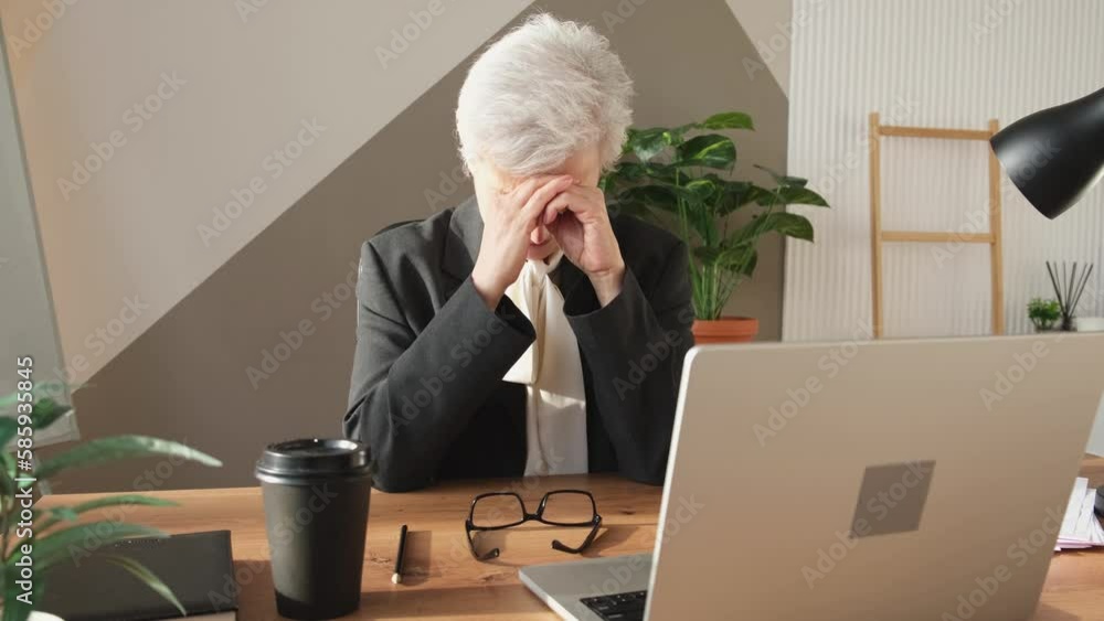 Middle aged senior woman touching temples experiencing stress in office ...
