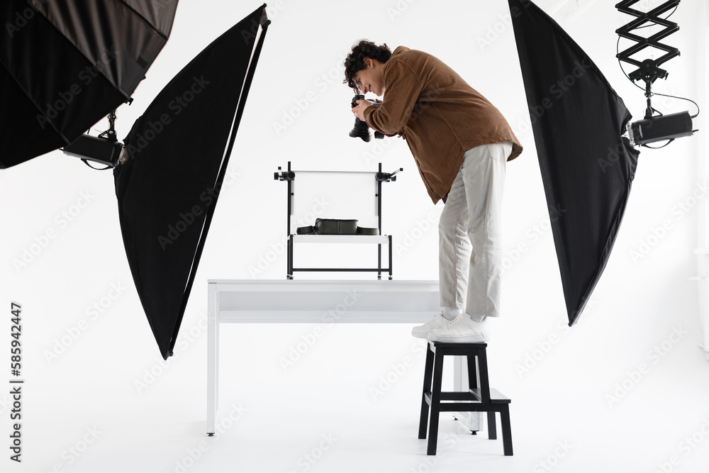 Professional male photographer standing on ladder and taking high angle ...