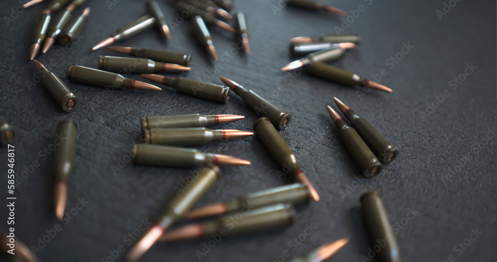 Scattered on a dark surface are bullets, cartridges for a kalashnikov ...