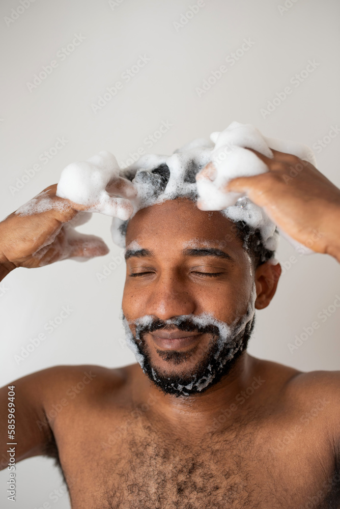 Young handsome smiling African American man with a beard washing his ...