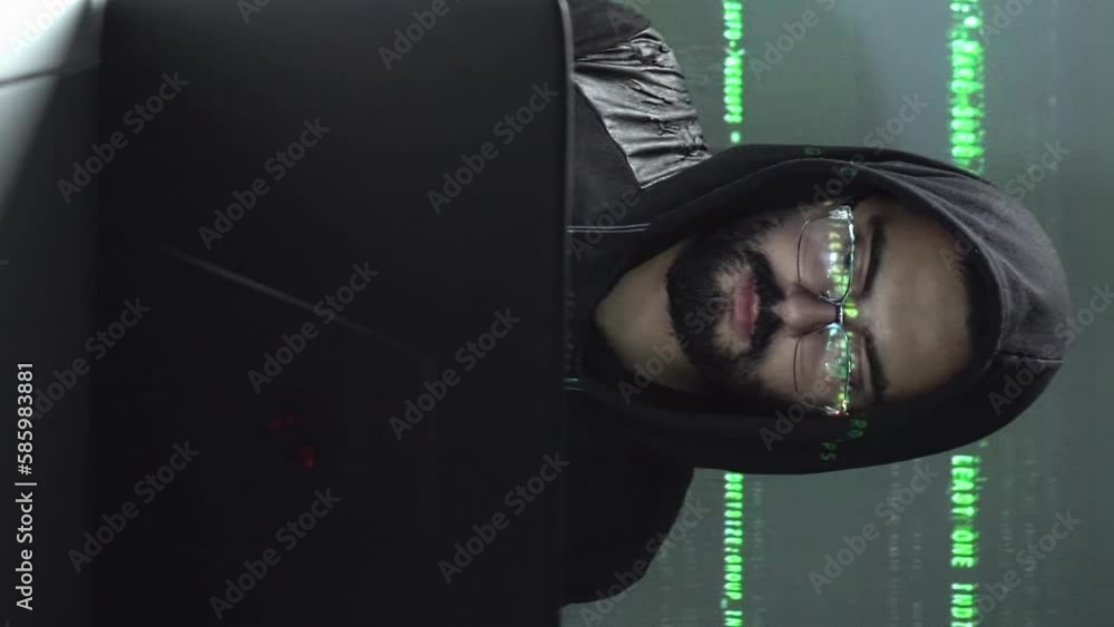 Vertical motion graphics of code rolling by face of hacker with laptop ...