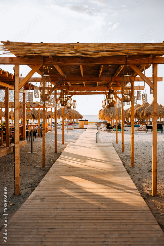 Terrace with thatched roof at the entrance to the wooden pontoon on the ...
