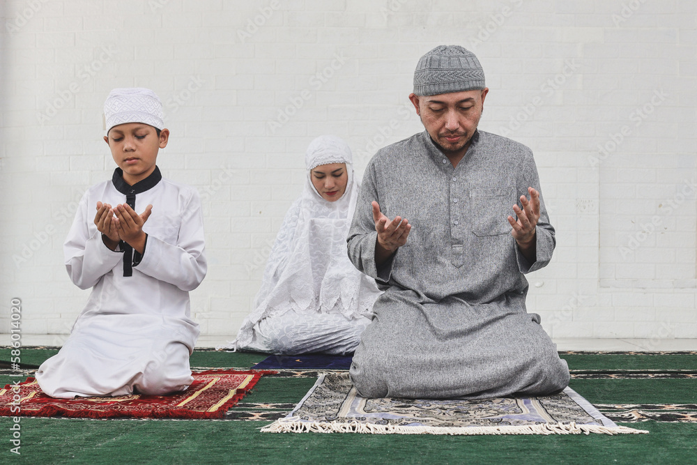 Asian muslim family are sitting and praying dua together at mosque ...