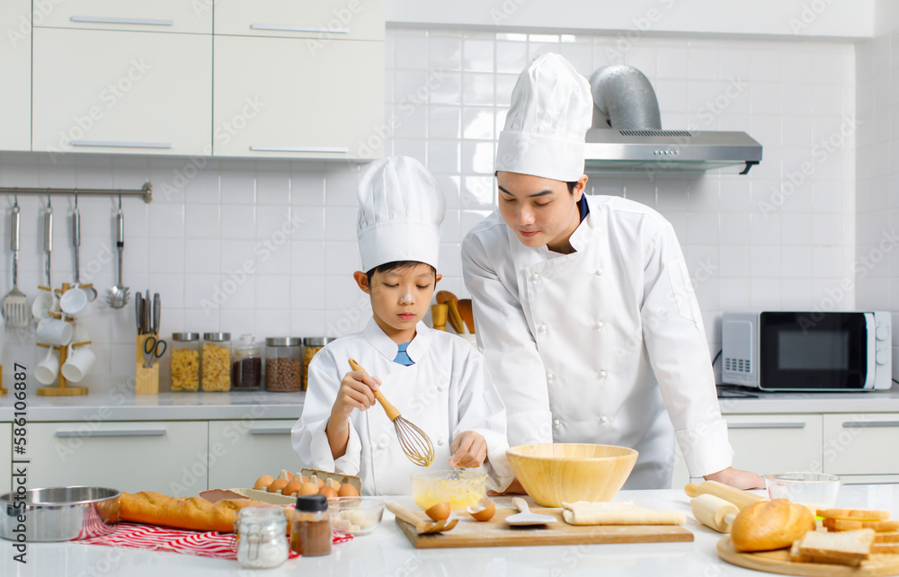 Asian young little boy pastry chef in white uniform with tall cook hat ...