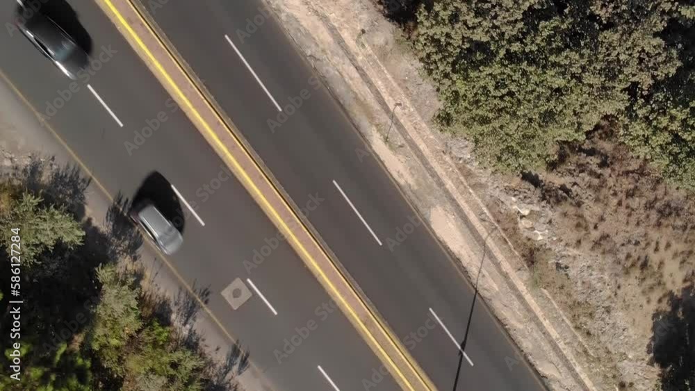 Cars driving on two lane asphalt road through nature, aerial top down ...