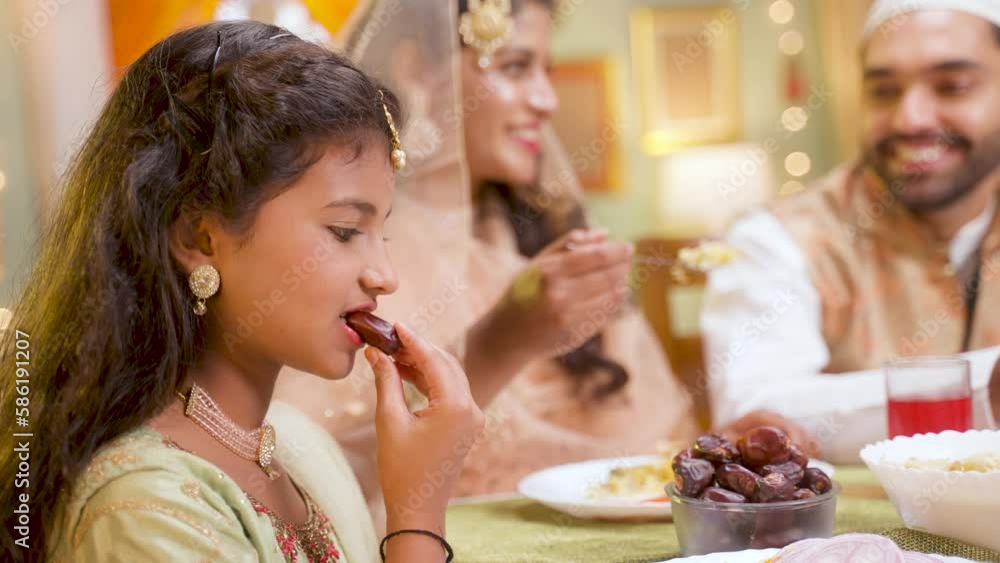Happy excited girl eating dates while having dinner during Ramadan ...