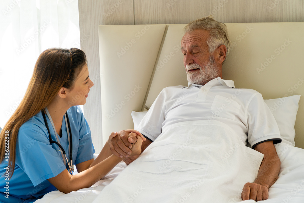 The nurse holds the hand of the elderly patient on the bed. Encouragement to recover from ...