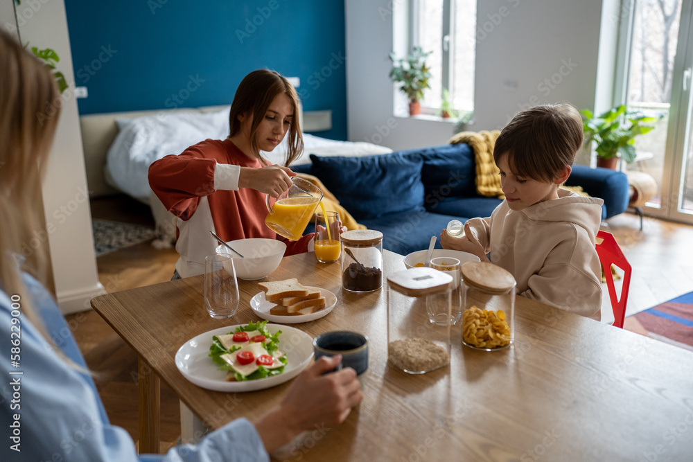 Mother and two kids sitting at kitchen table at home, family of three ...