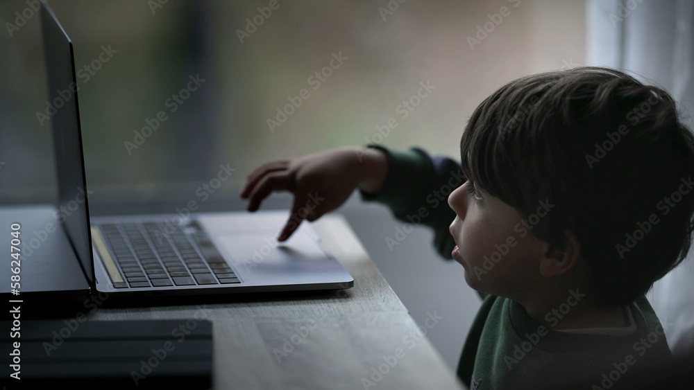 Little boy using computer at home. Child trying to male laptop work ...