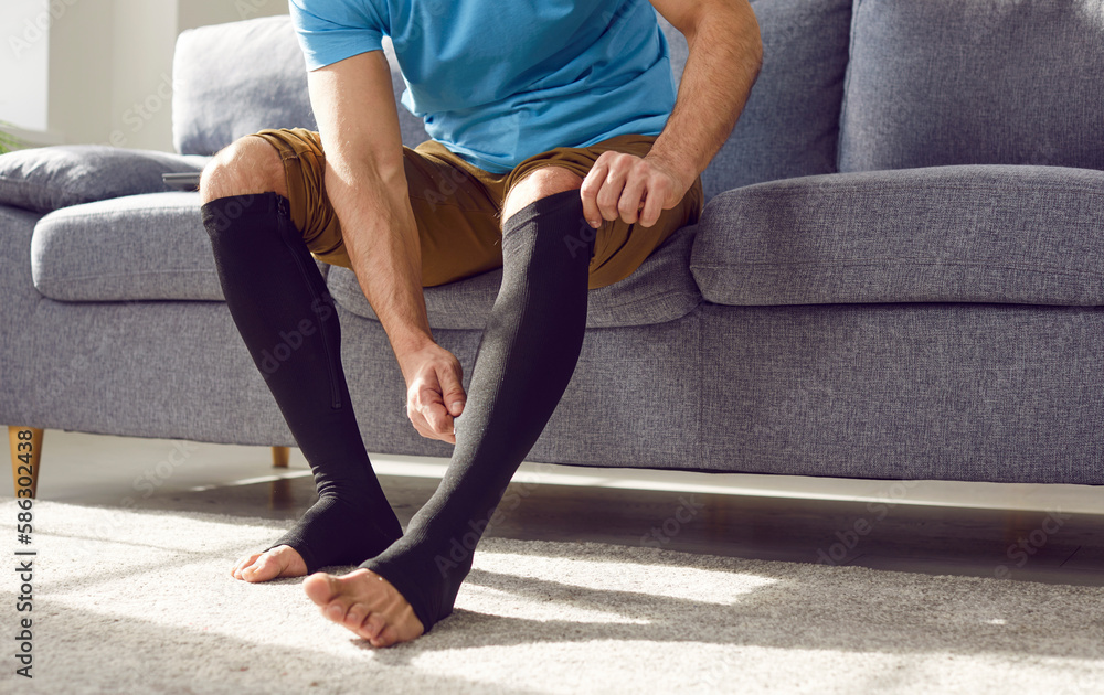 Cropped photo of a man putting on black medical compression stockings ...