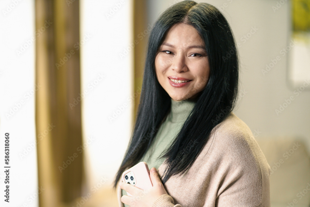 Mature and positive Asian woman with thick, luscious hair holds her ...