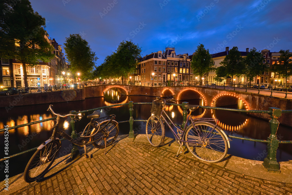 Night view of Amsterdam cityscape with canal, bridge with bicycles and ...